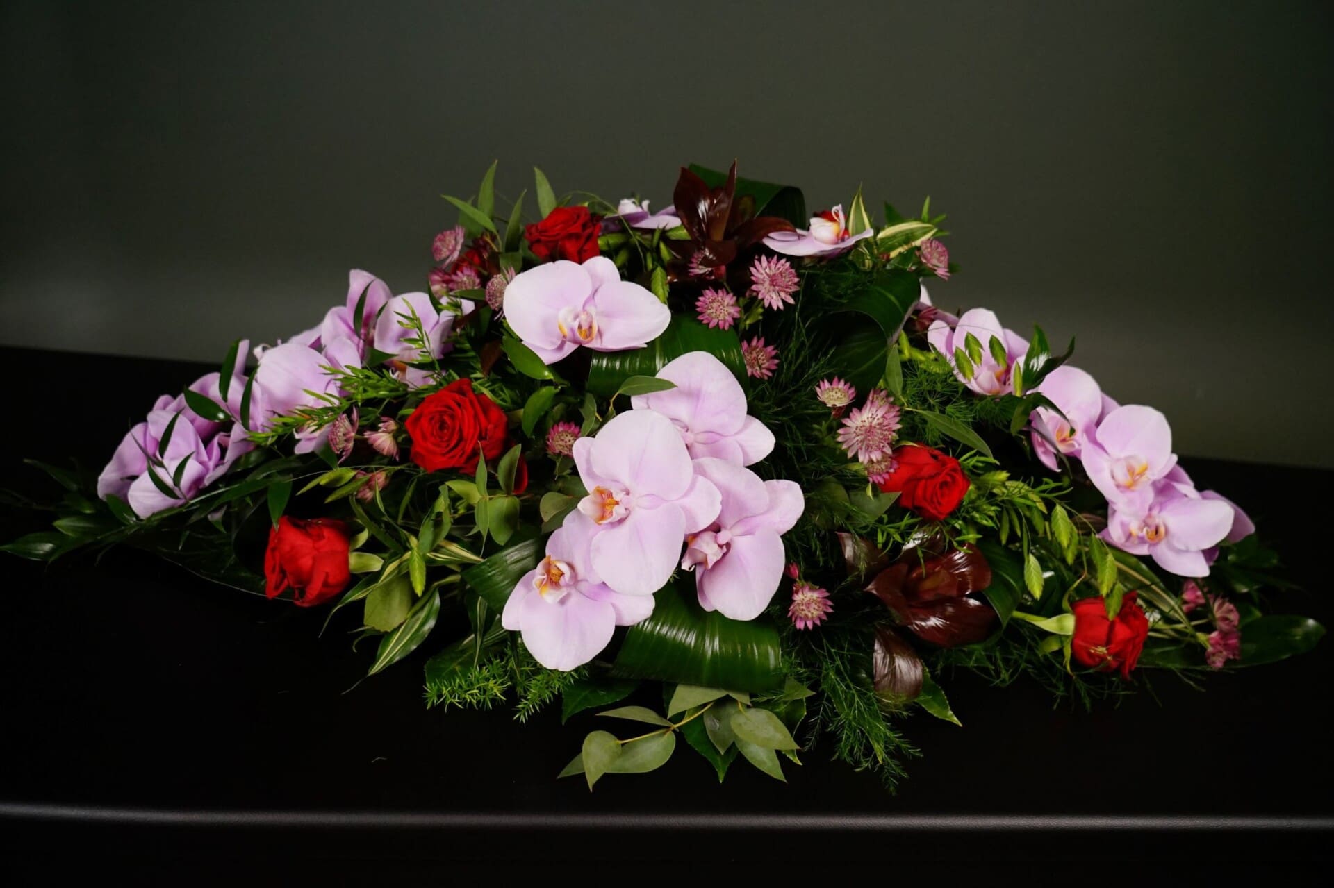 Rouwstuk roze orchidee en rode rozen
