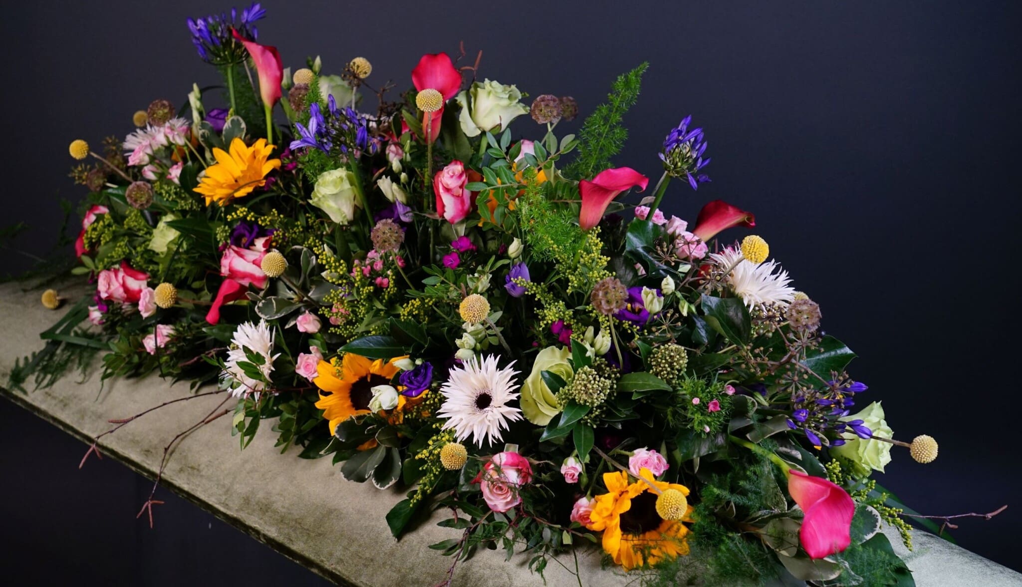 Kistarrangement uit bonte veldachtige bloemen. Bloemrijk kiststuk